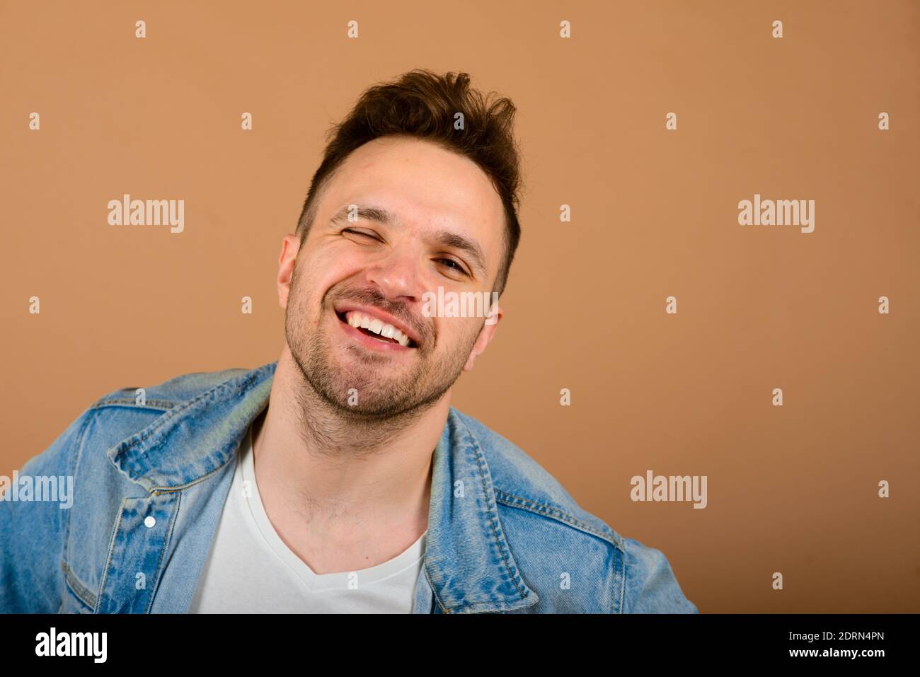 Handsome man standing and smiling isolated on the light brown studio ...