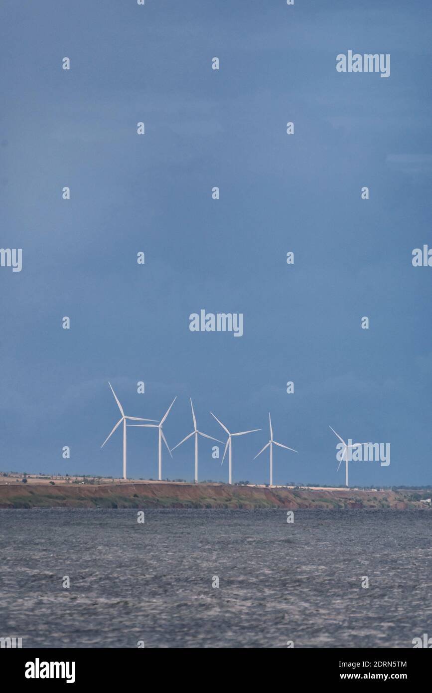 Wind wheels in the sea on blue sky background. Wind energy. Vertical ...