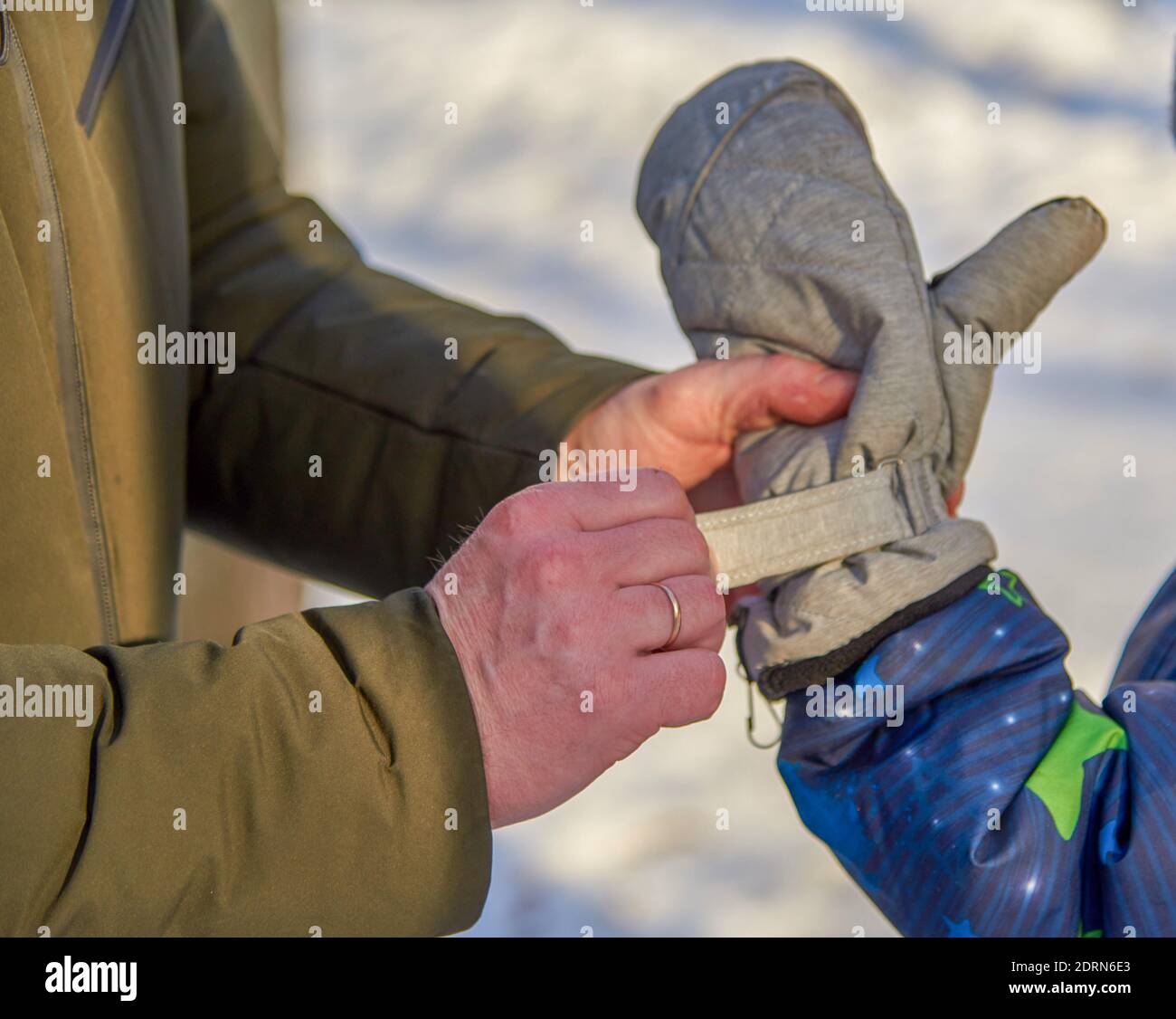 A man puts a mitten on his son's hand Stock Photo - Alamy