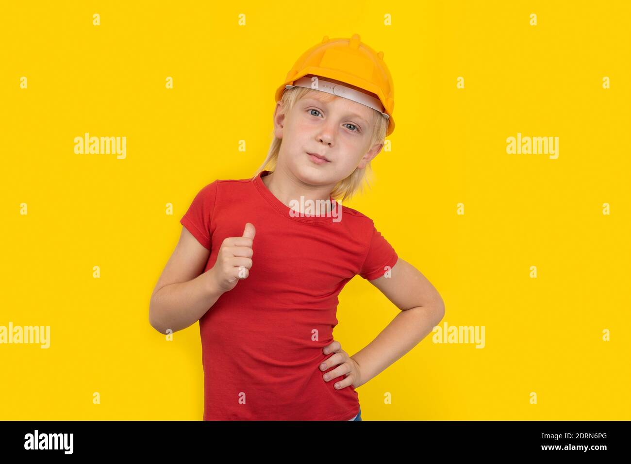 Serious teen boy in protective orange hard hat shows the gesture well ...