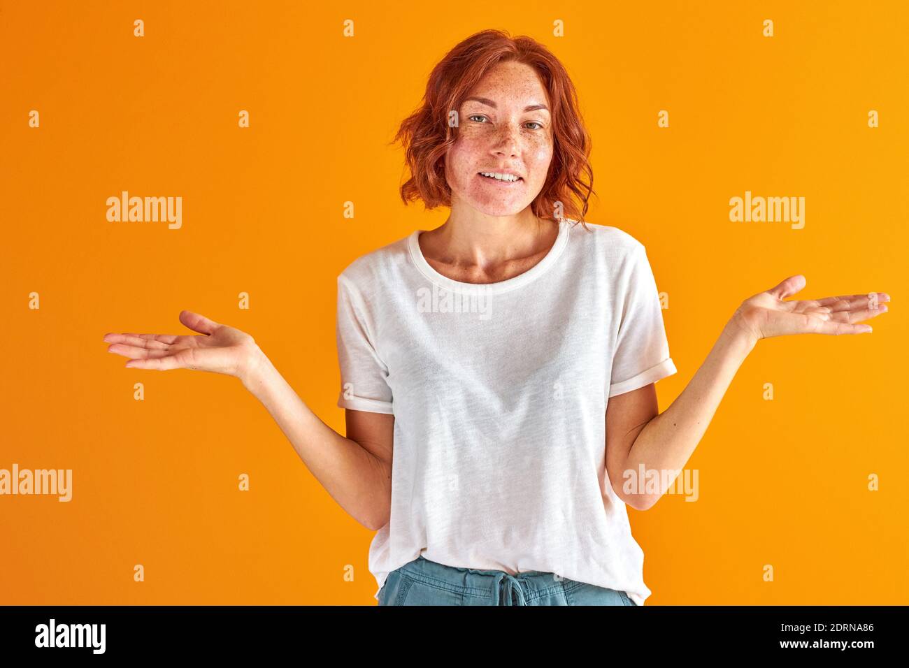 woman shrugging in studio on orange background, young lady in casual ...
