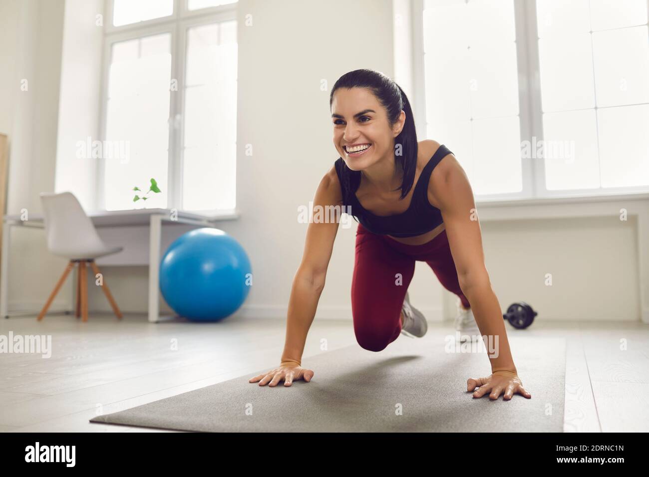 Beautiful active sports woman trains on a mat and does leg exercises at ...