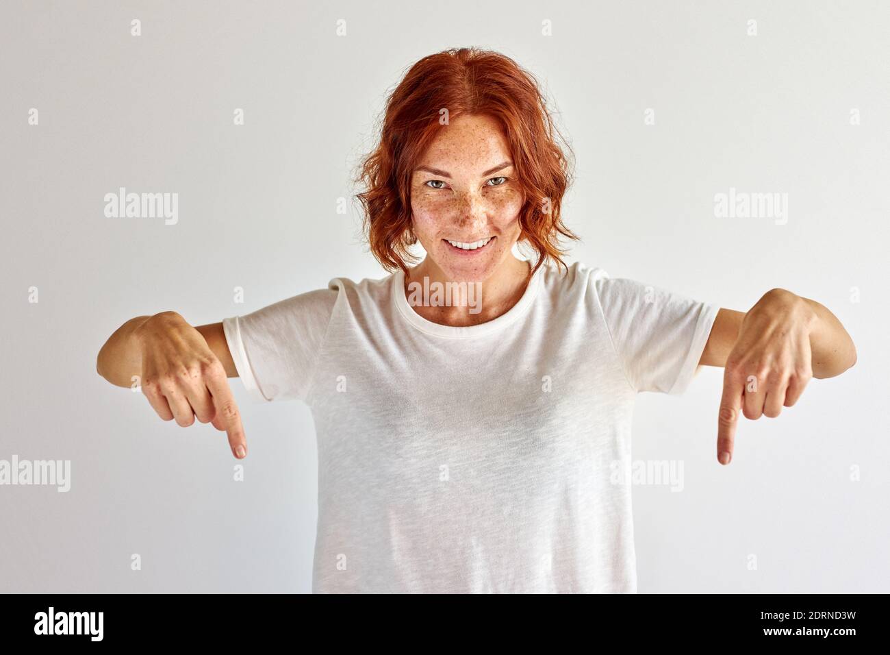 woman is pointing finger down, index finger isolated over white studio ...