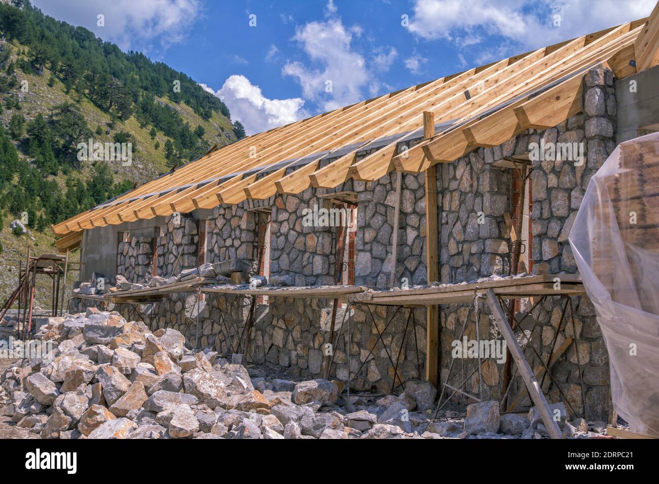 View of house construction in mountain area – stone walls, wooden roof ...