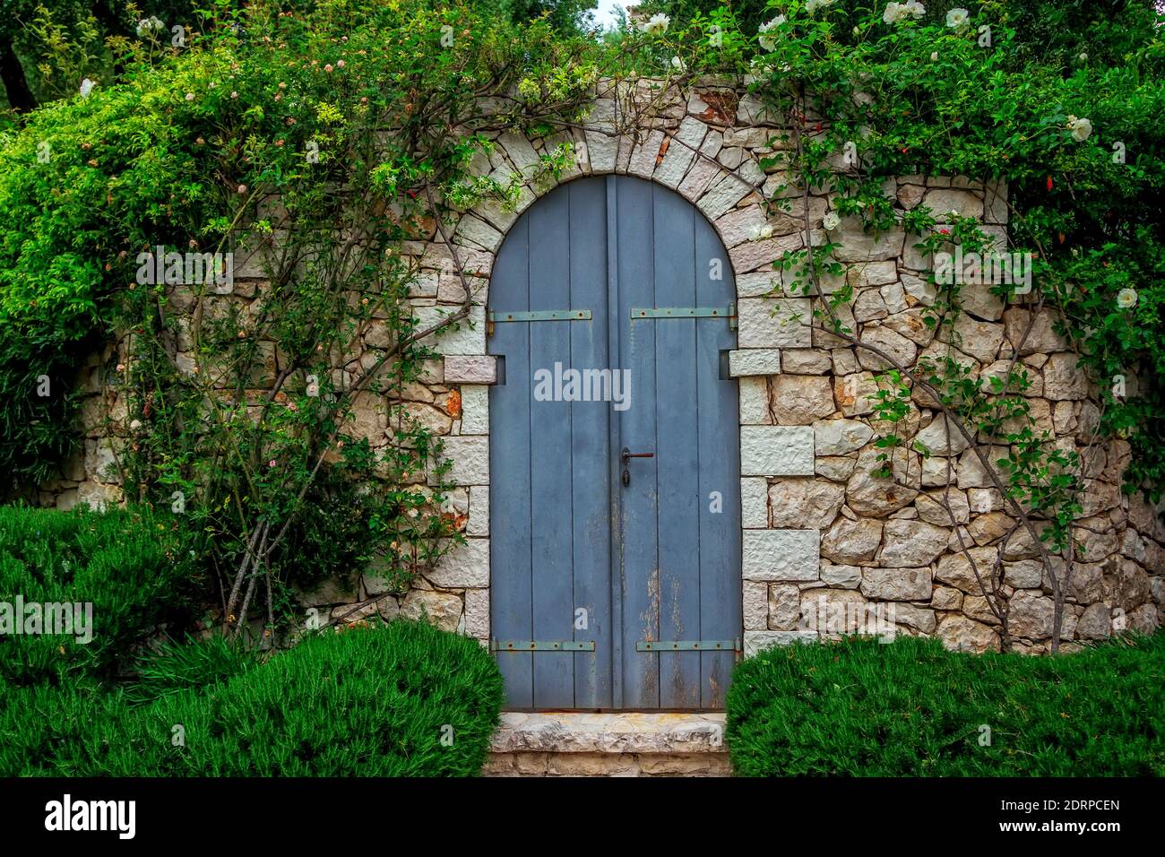 Gray wooden arcade door with metal rivets at vintage style stone wall ...