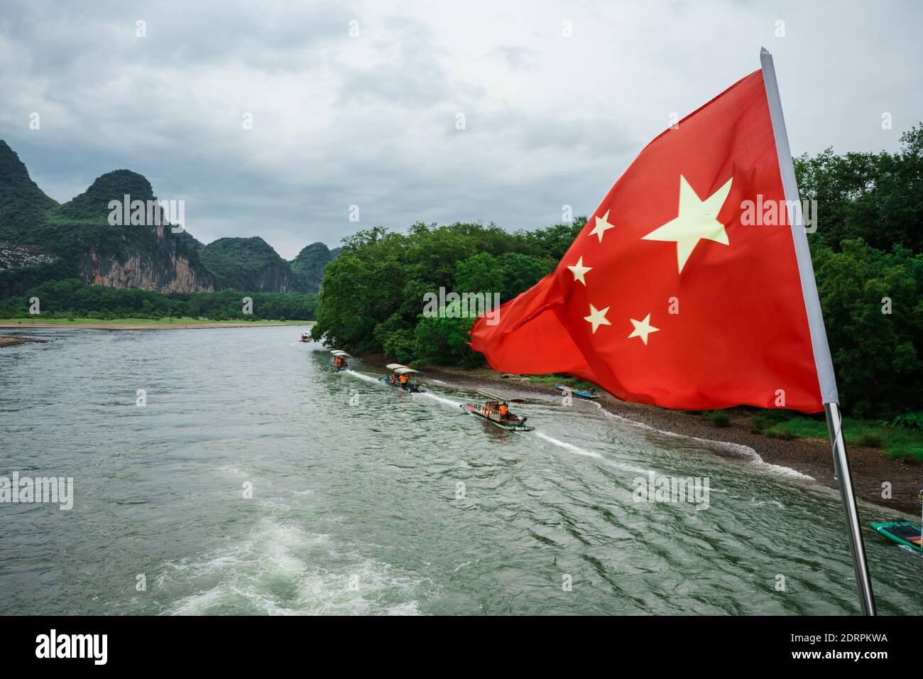Red Flag Waving By River Against Mountains And Sky Stock Photo - Alamy