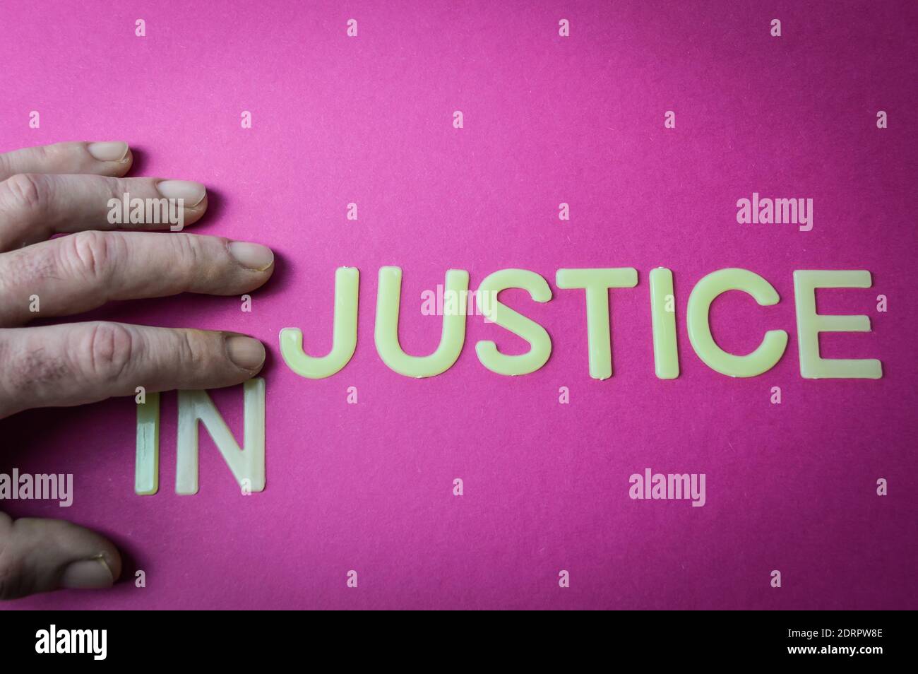 Human fingers sliding two letters to the word Injustice to make it ...