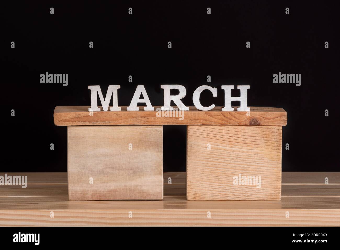 Month March from wooden blocks on wooden shelf. Black background ...