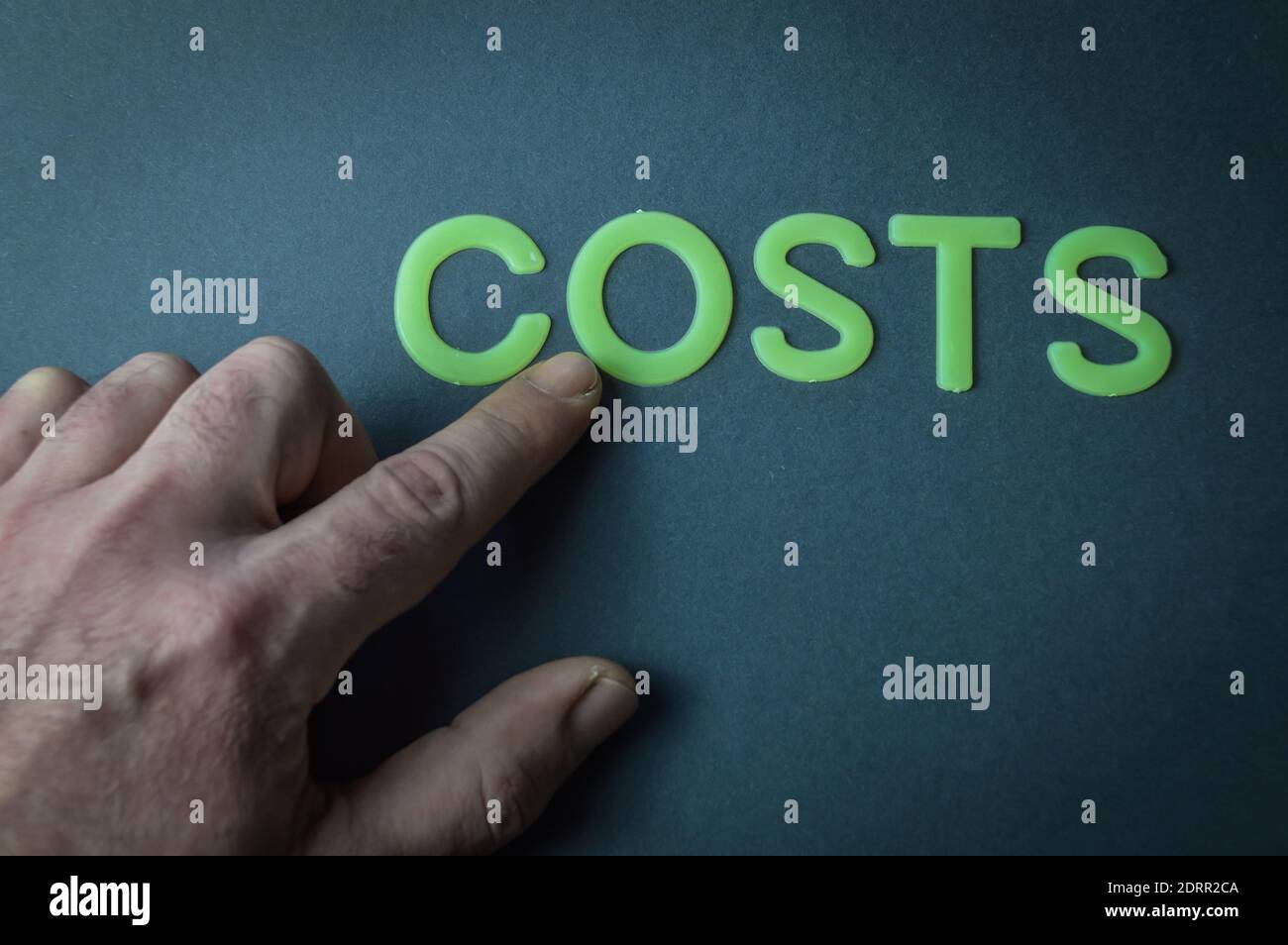Human finger pointing the word Costs written with plastic letters on ...