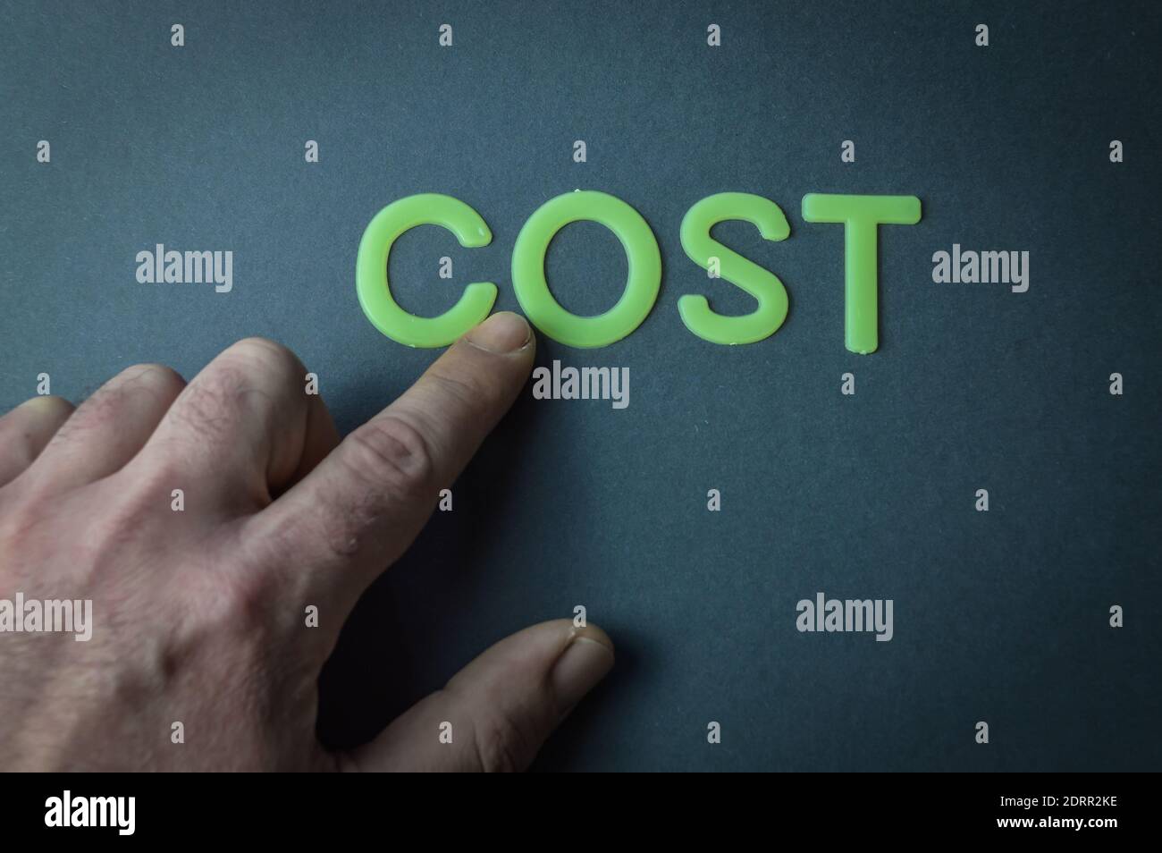 Human finger pointing the word Cost written with plastic letters on ...