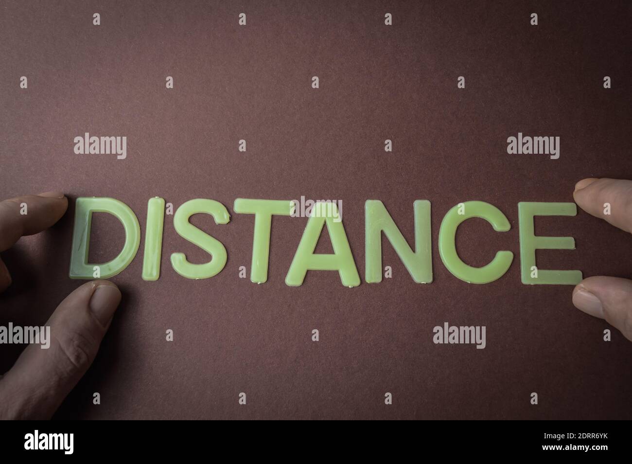 Human fingers holding the word Distance written with plastic letters on ...