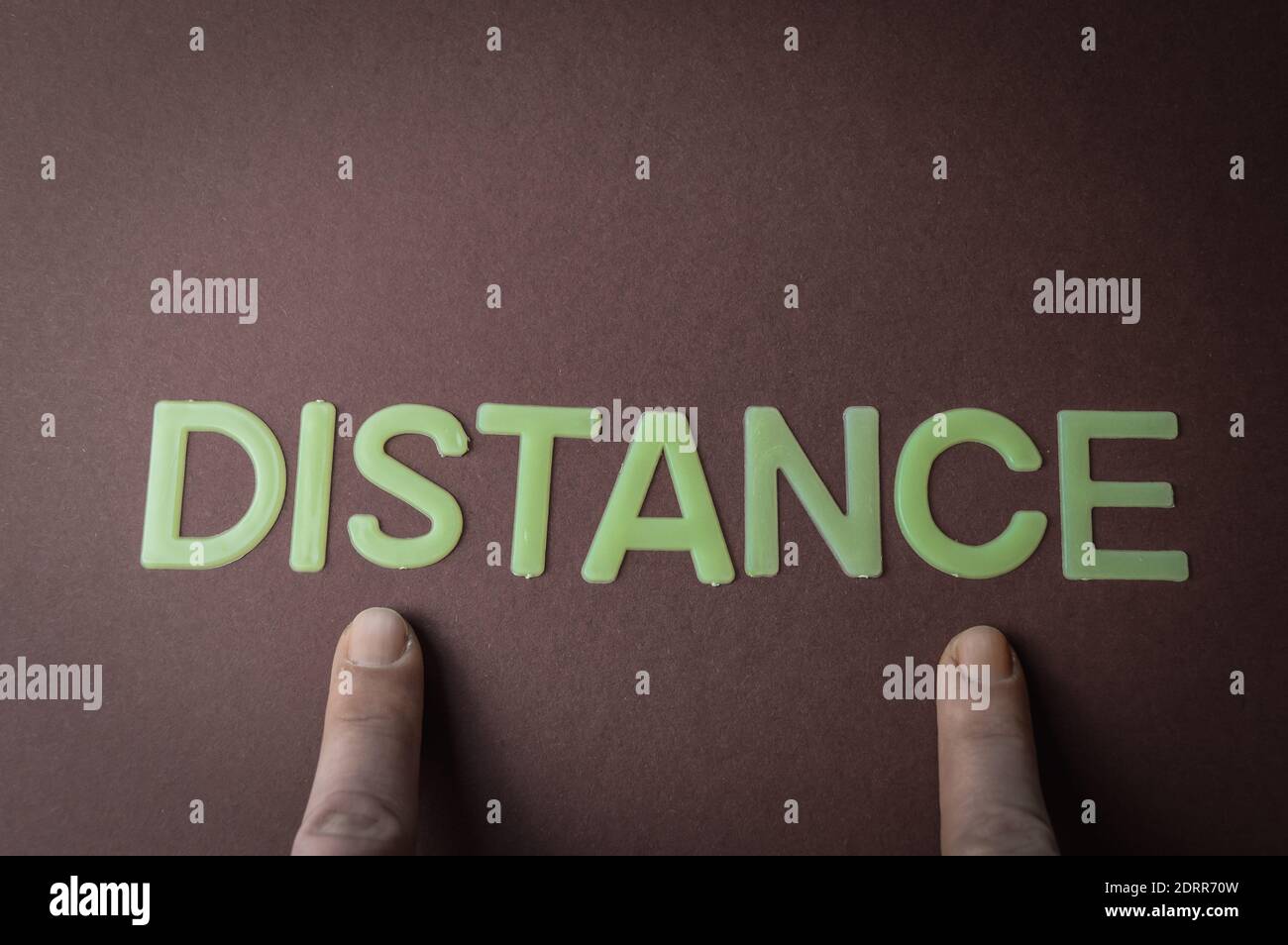 Two human fingers distant under the word Distance written with plastic ...
