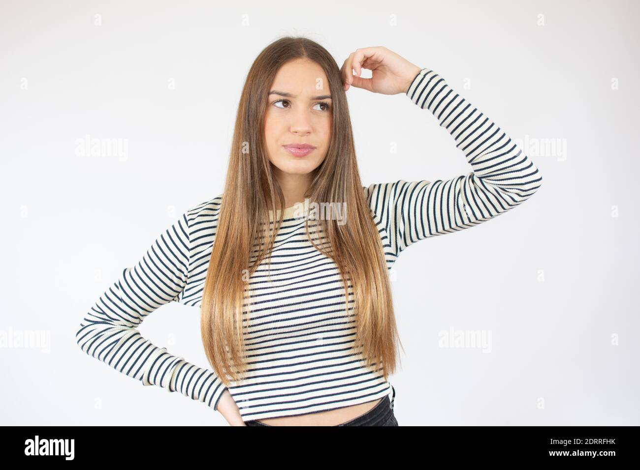 Teenager girl with striped t-shirt having doubts while scratching head ...