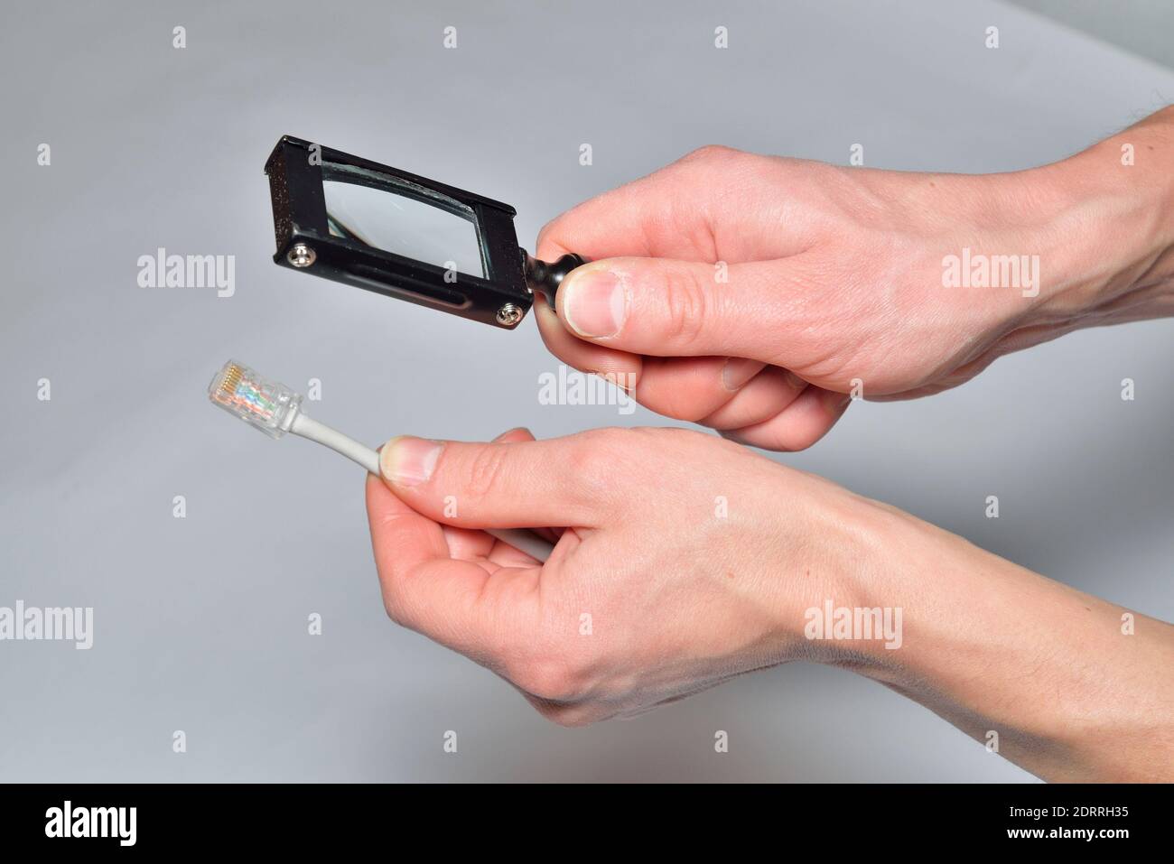 Hands of the installer Ethernet hold the magnifying glass and cable ... Hands of the installer Ethernet hold the magnifying glass and cable ...