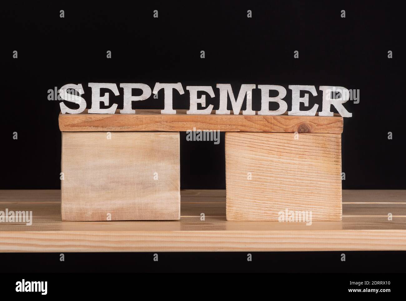 Word September from wooden letters on black background. Front view ...