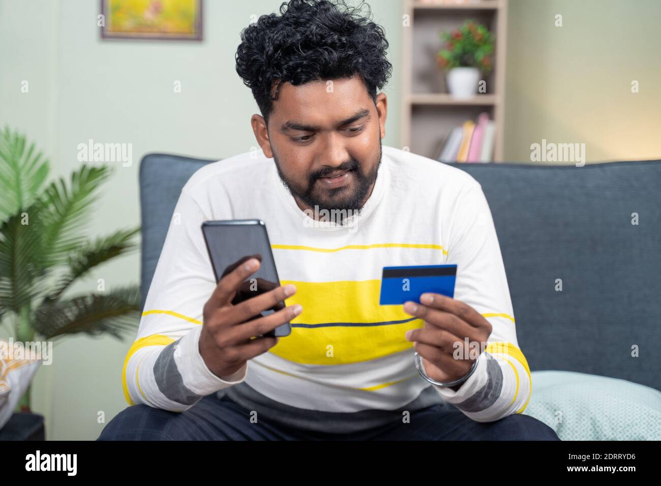 young man entering card details on mobile phone for online purchase ...