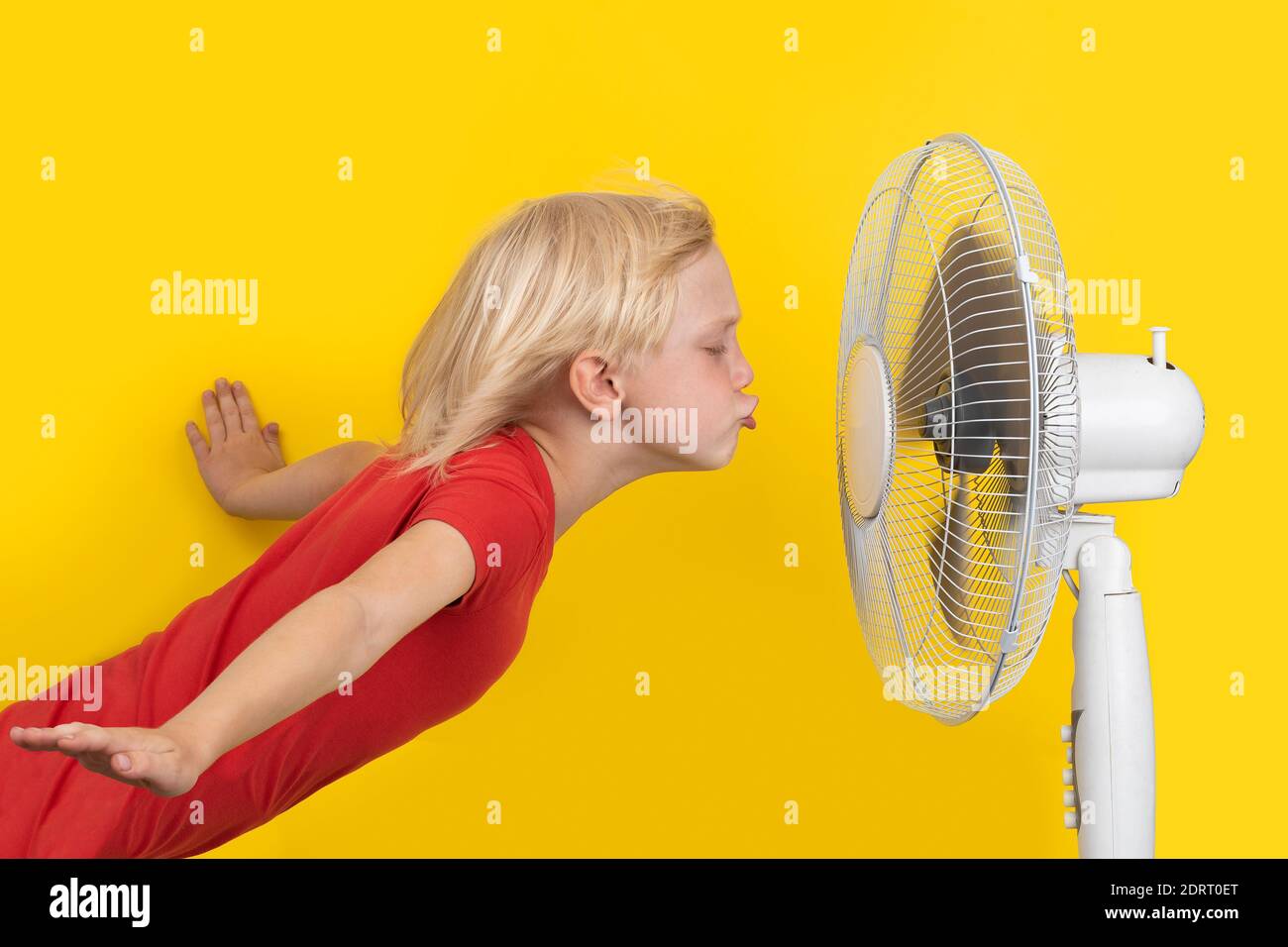 Cute boy refreshing from the heat in front of the fan. Hot weather ...