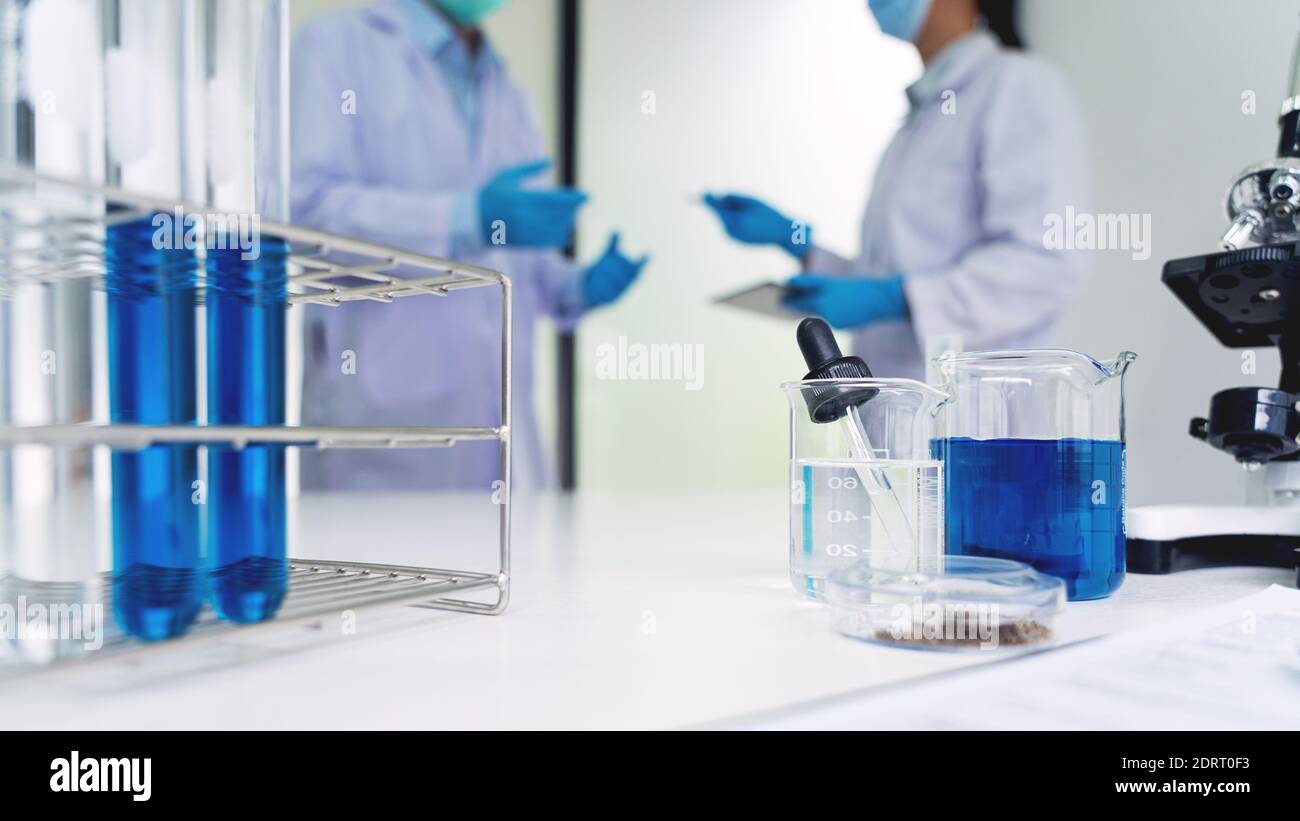 Attractive young scientist team in lab coat and safety goggles working ...