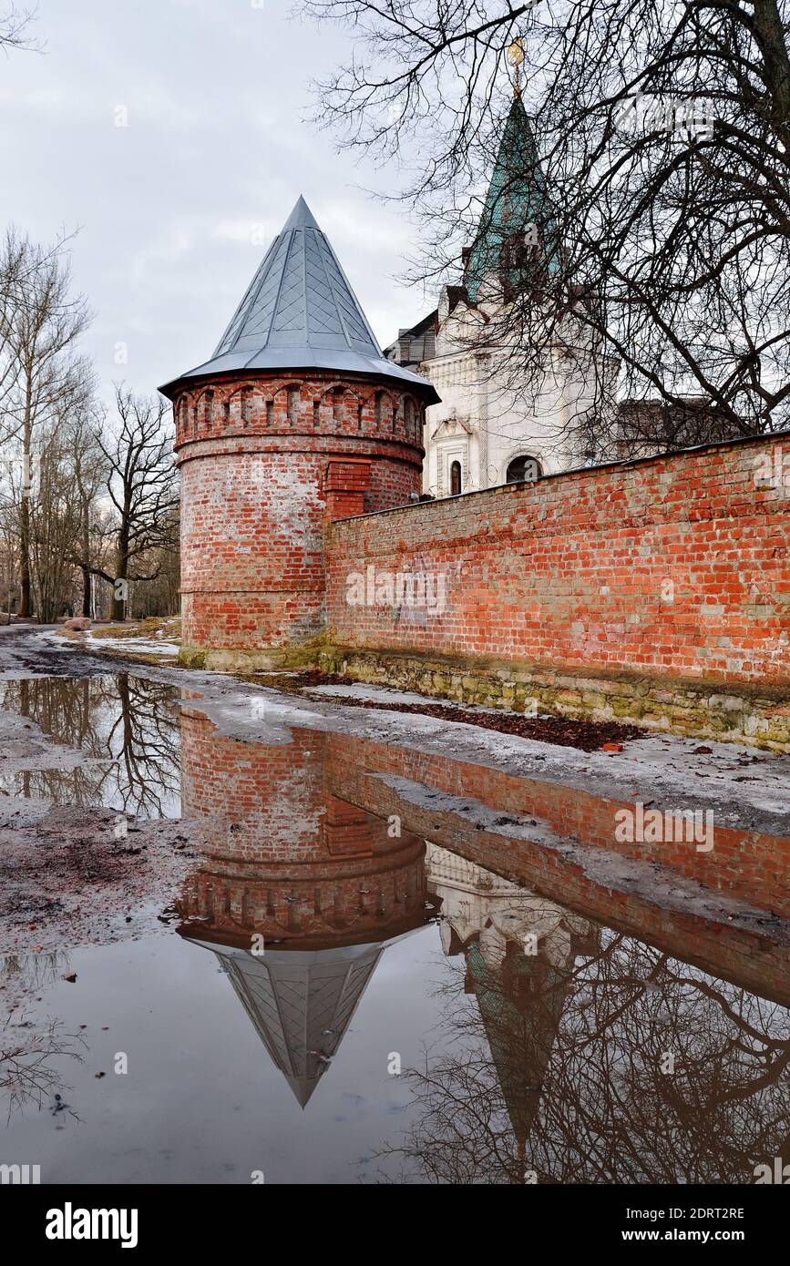 The red brick tower reflected in a puddle of melt in the spring Stock ...