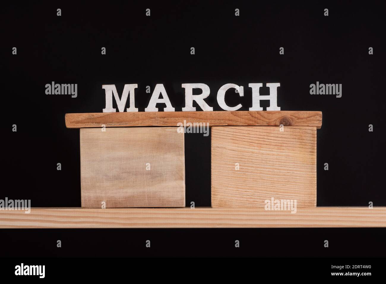 Word March written on wooden blocks on wooden shelf on black background ...