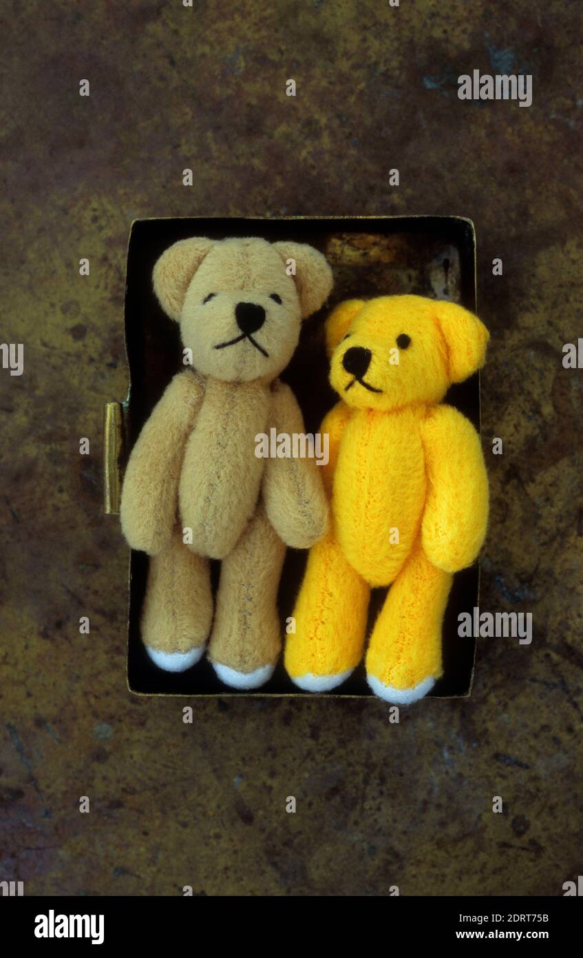 Two small teddy bears one beige and one yellow lying in brass lid Stock ...