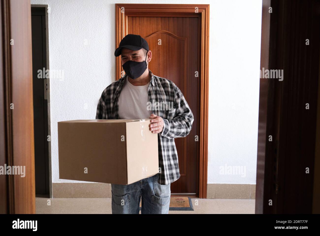 Delivery senior man waiting at the door holding a package. Delivery ...