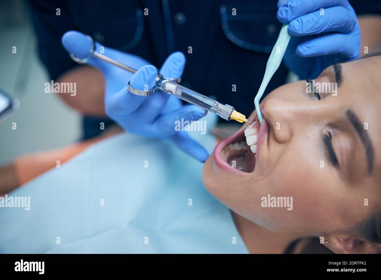 Dentist doing injection in woman gum in office Stock Photo - Alamy
