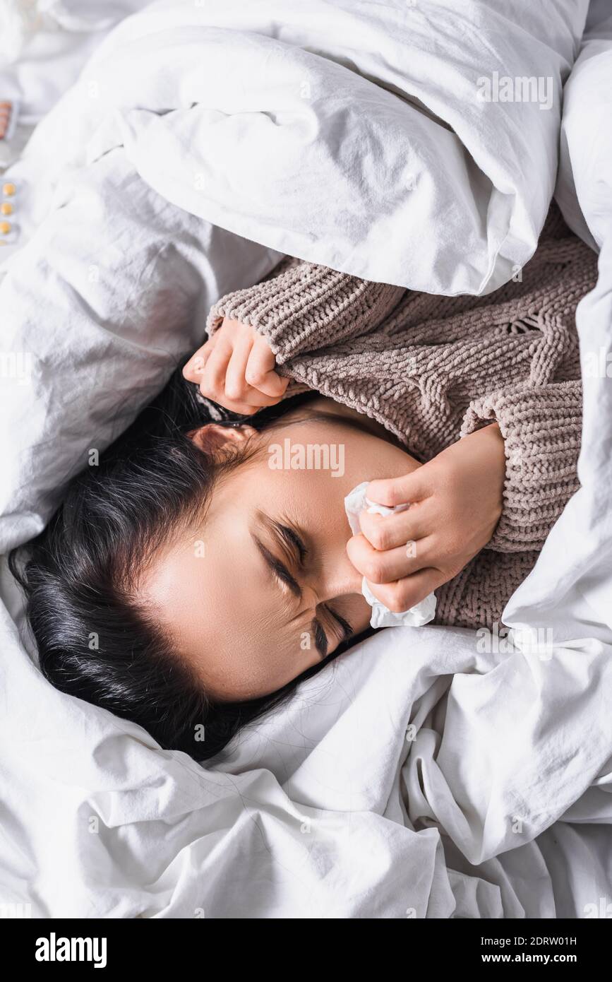 top view of sick young brunette woman with tissue in bed Stock Photo ...