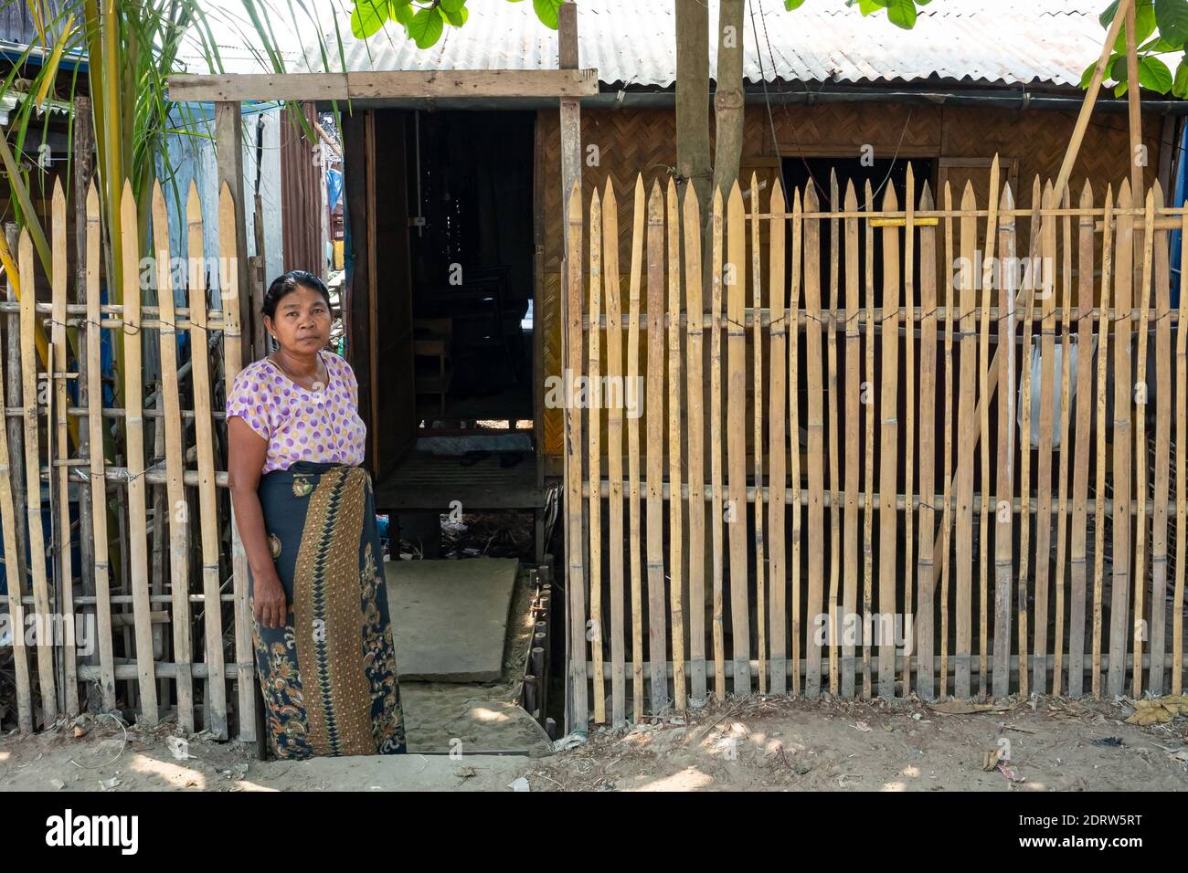 A woman standing in front of the gate in the wooden fence leading to ...