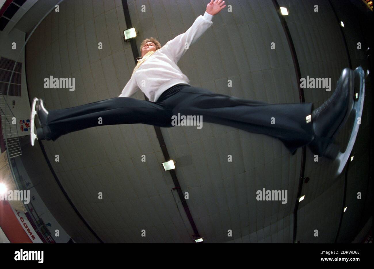 A fish eye lens captures a young man practicing with a jump on on ice ...