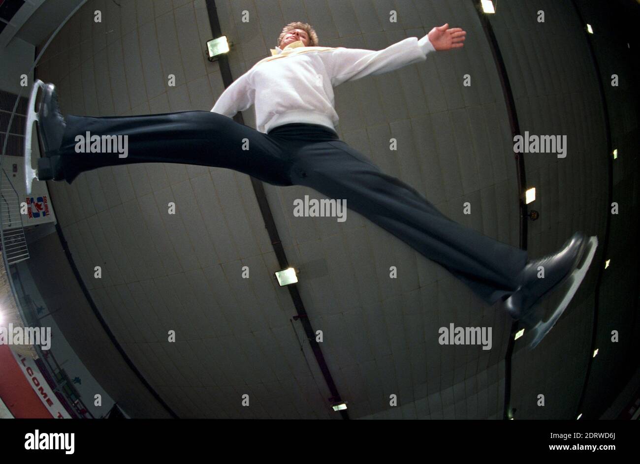 A fish eye lens captures a young man practicing with a jump on on ice ...