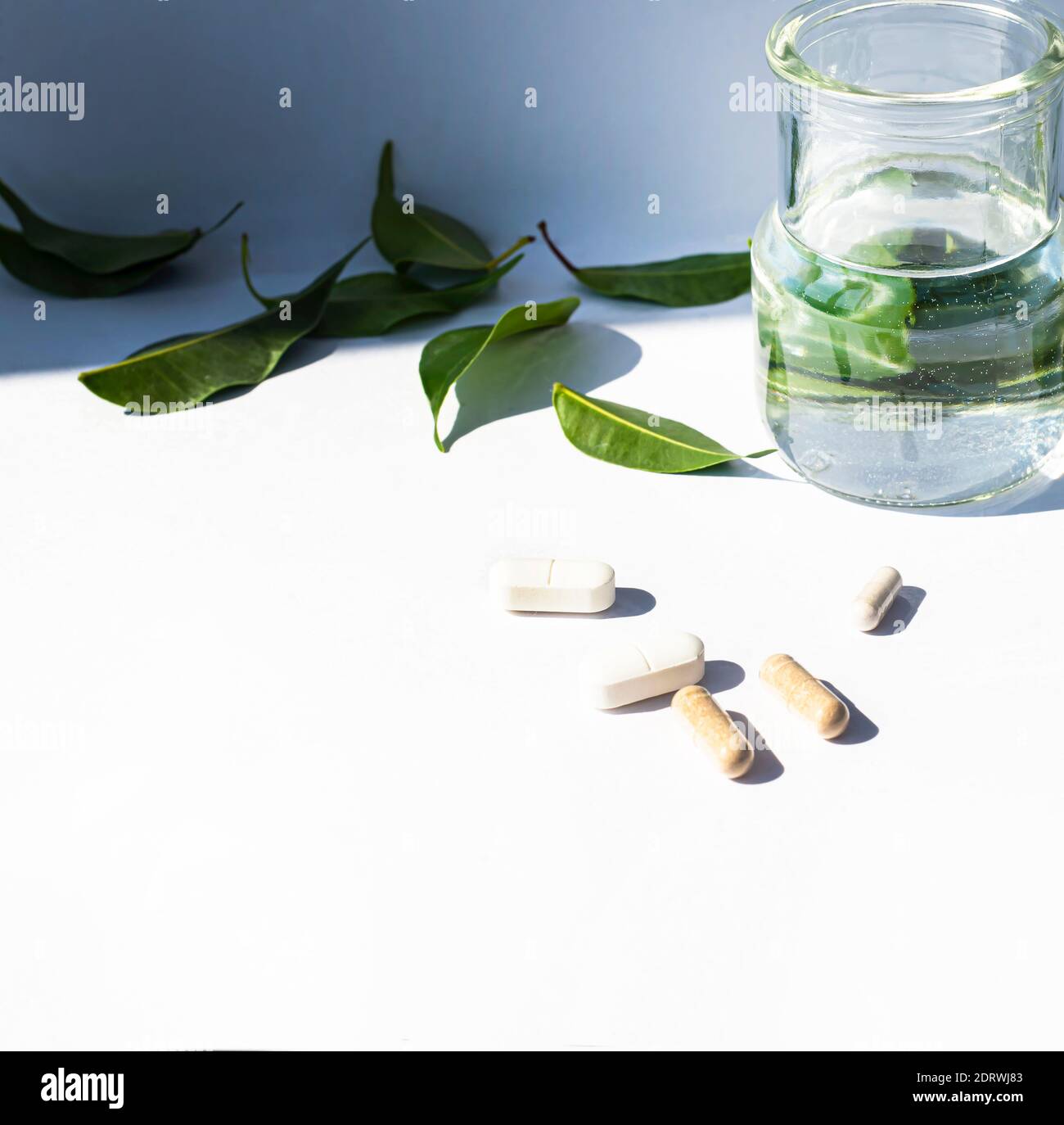 Square border with pills pills and a glass of water and green leaves ...