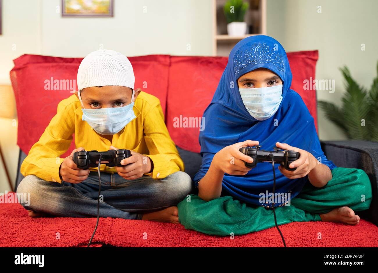 Two muslim kids with medical face mask busy playing video game using ...