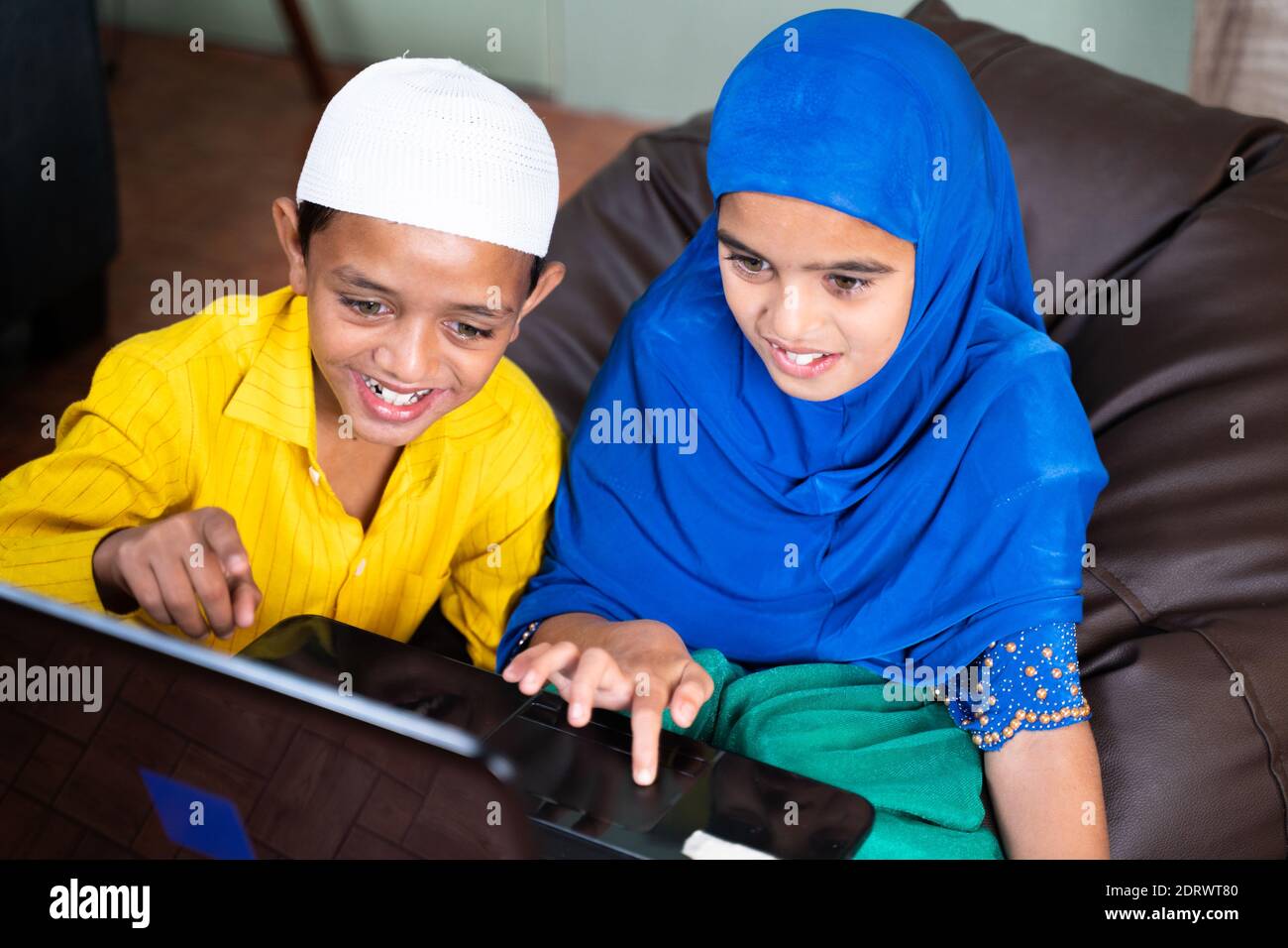 Two muslim teenager kids excited over using laptop at home - concept of ...