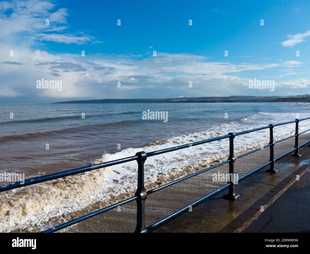 Waves and the promenade at high tide on the beach at Filey a popular ...