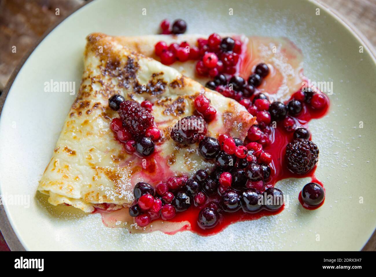 A homemade crepe served with honey and defrosted frozen fruit from a ...