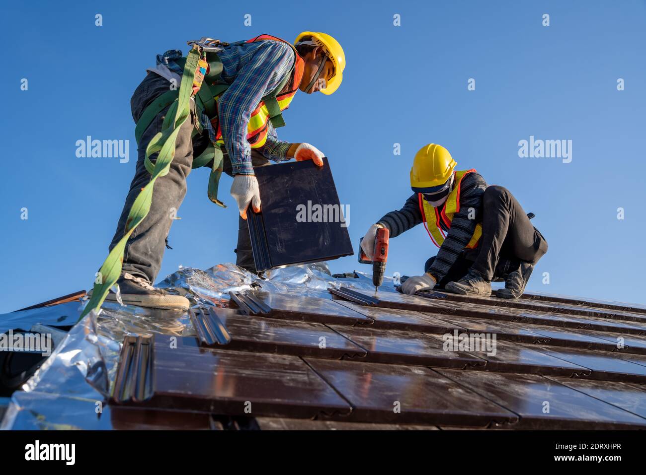 Two work construction worker install new ceramic tile roof with Roofing ...