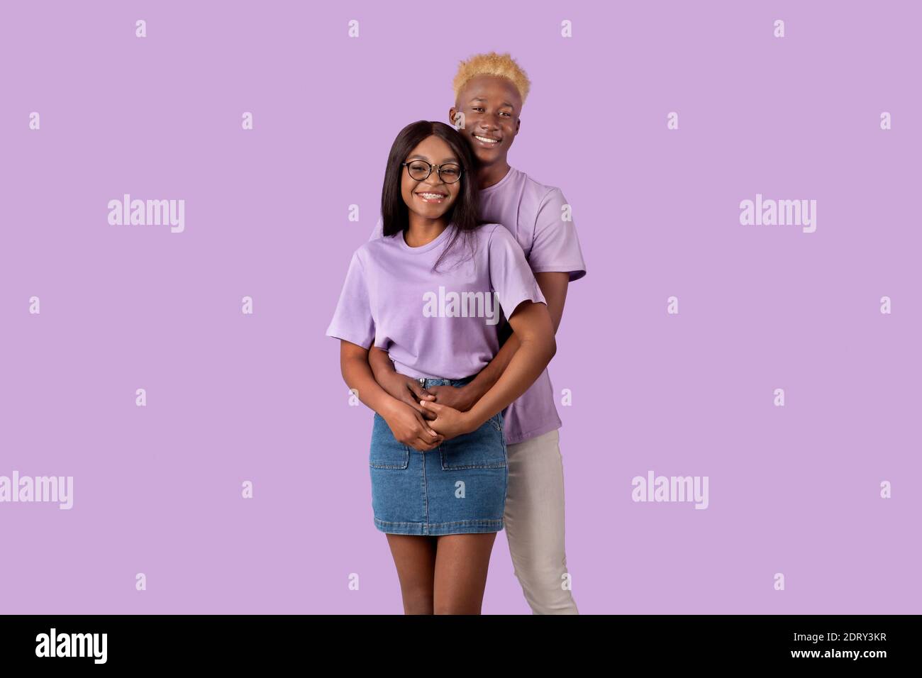 Cool millennial black couple hugging over violet studio background ...