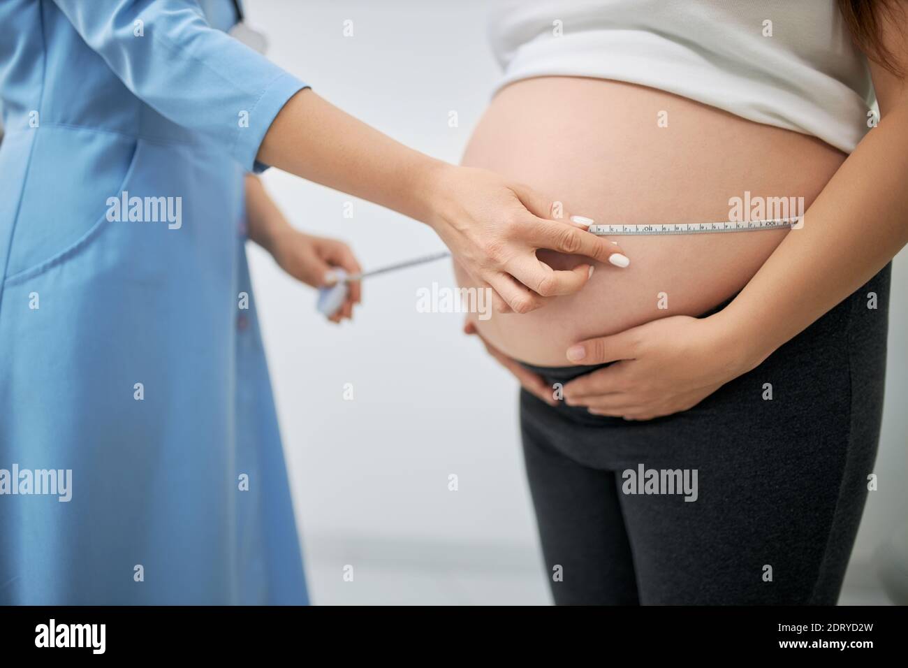 Close up of female doctor measuring tummy of pregnant woman at modern ...