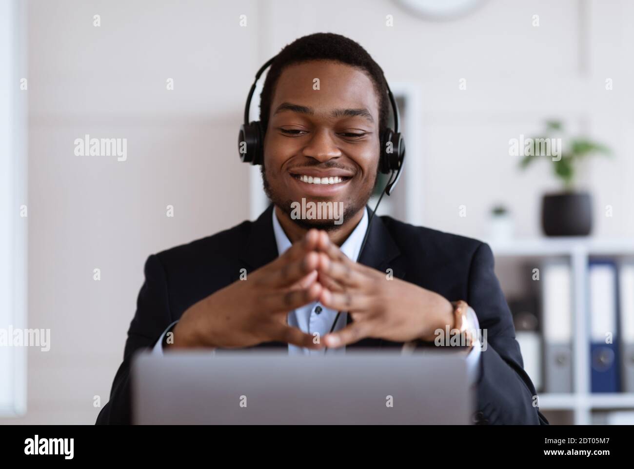 Closeup of black manager with headset using laptop, office interior ...