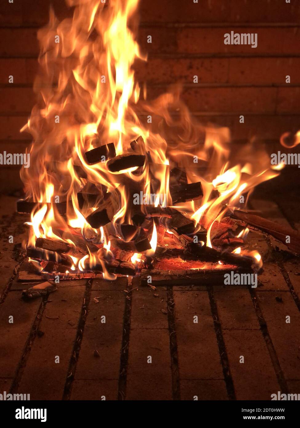 A vertical closeup of a bright campfire on a brick surface Stock Photo ...