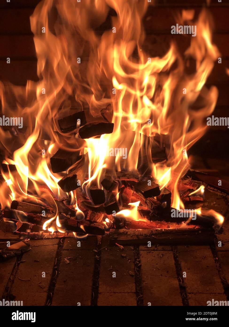 A vertical closeup of a bright campfire on a brick surface Stock Photo ...
