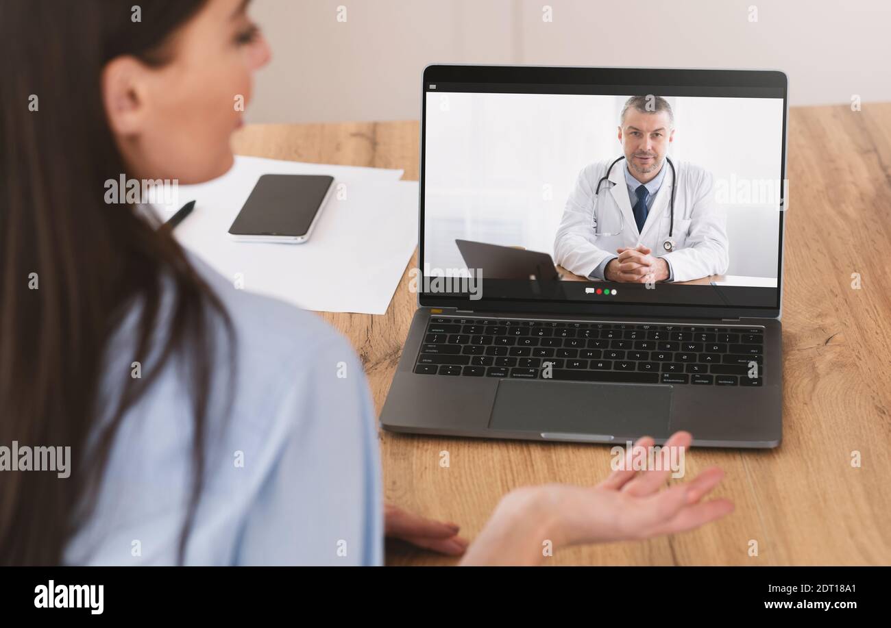 Cybermedicine. Female patient chatting with doctor online using laptop ...