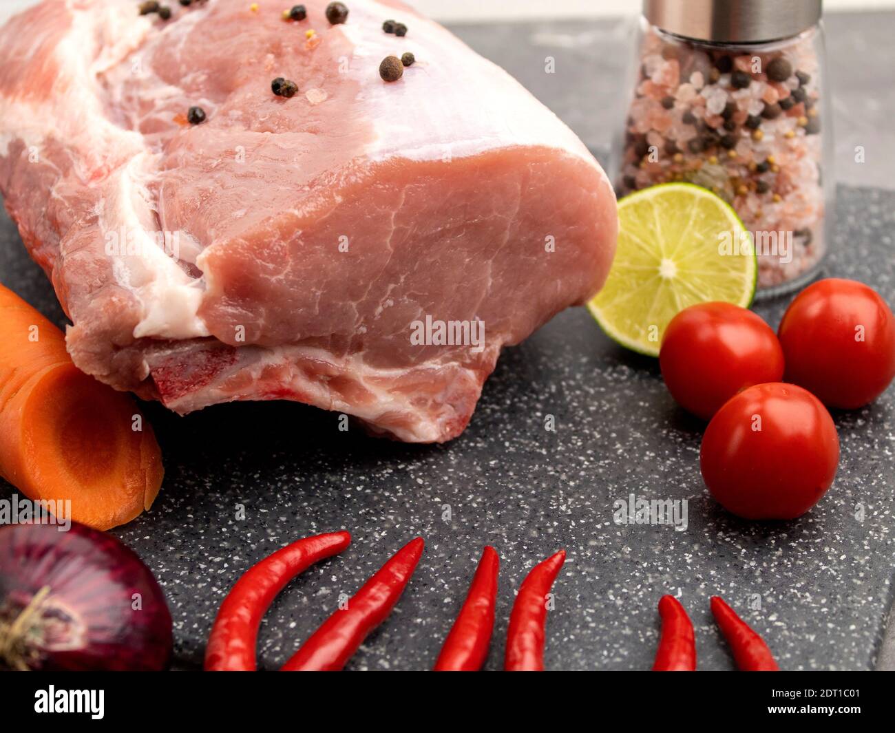 Raw pork meat on a marble board with spices and vegetables Stock Photo ...