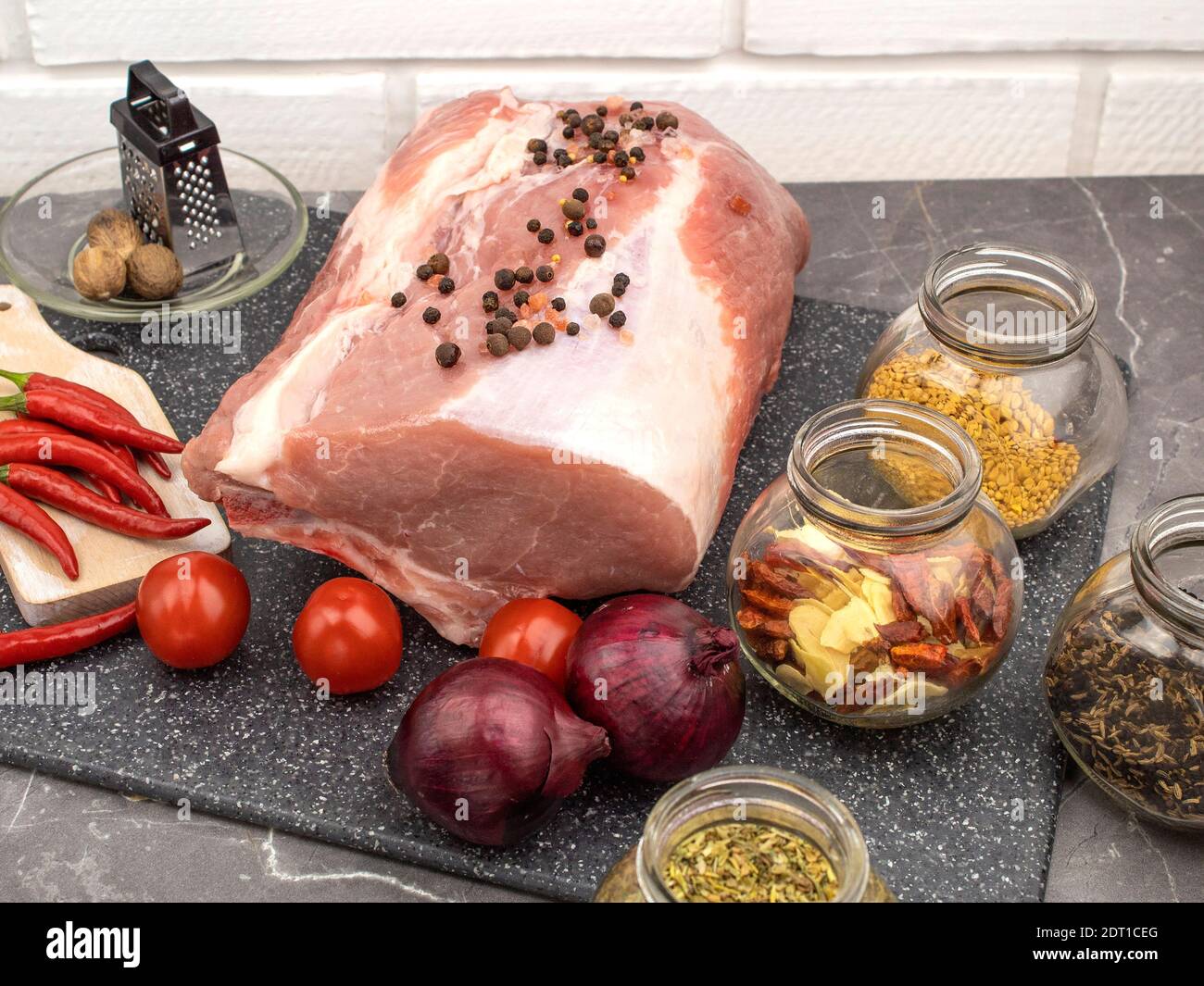 Raw pork meat on a marble board with spices and vegetables Stock Photo ...