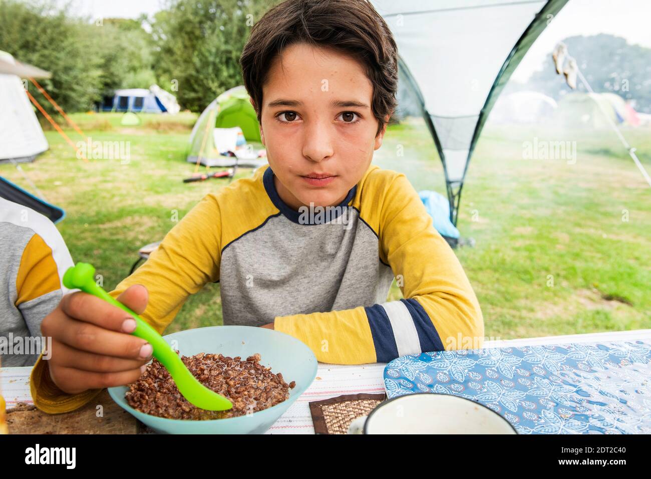 Boy eating breakfast at camp site Stock Photo - Alamy