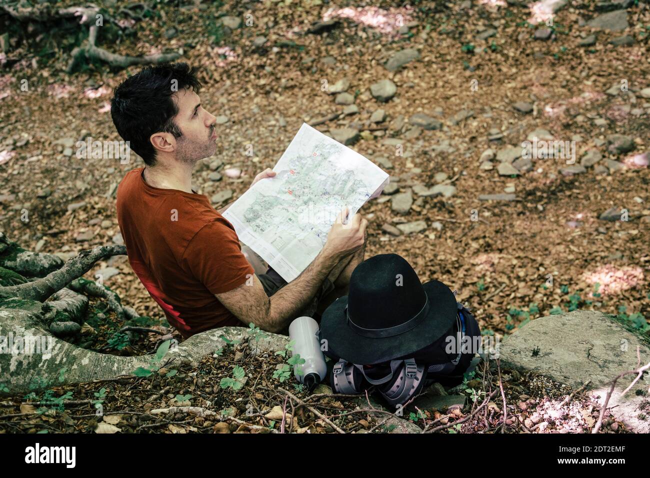 Hiker locating a path in the forest with a map Stock Photo - Alamy