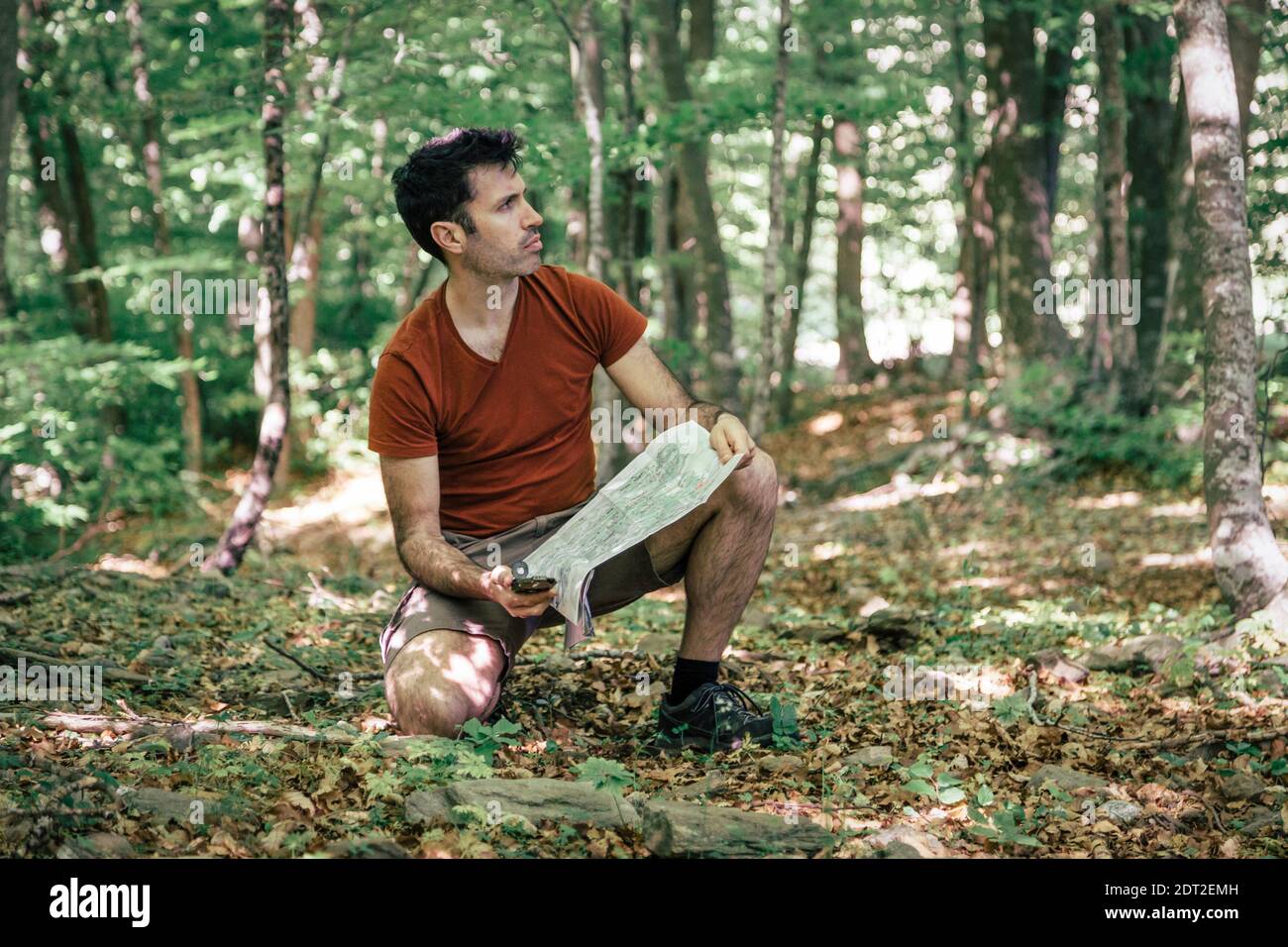 Hiker locating a path in the forest with a compass and map Stock Photo ...