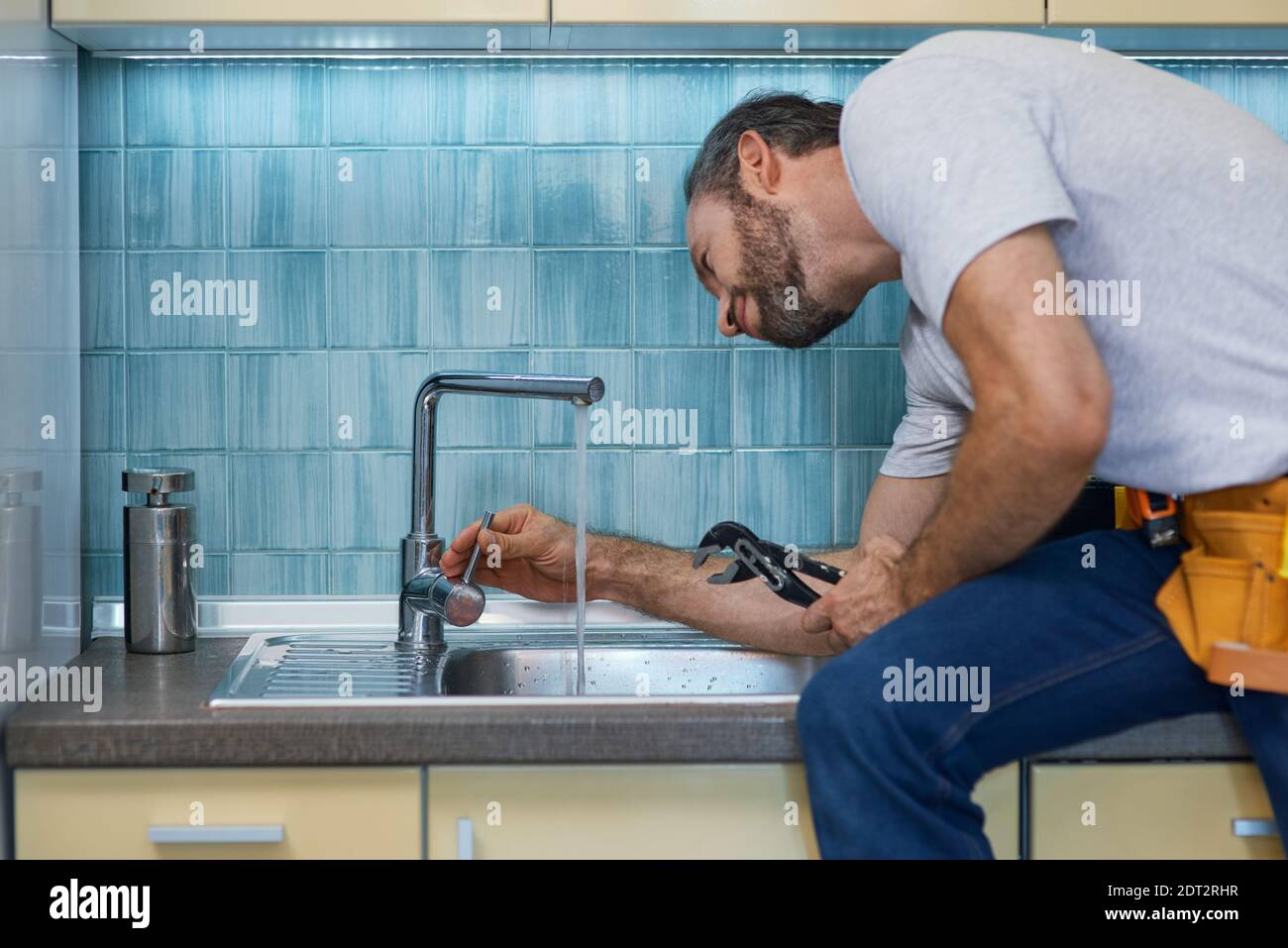 Professional plumber looking concentrated, using pipe wrench while ...