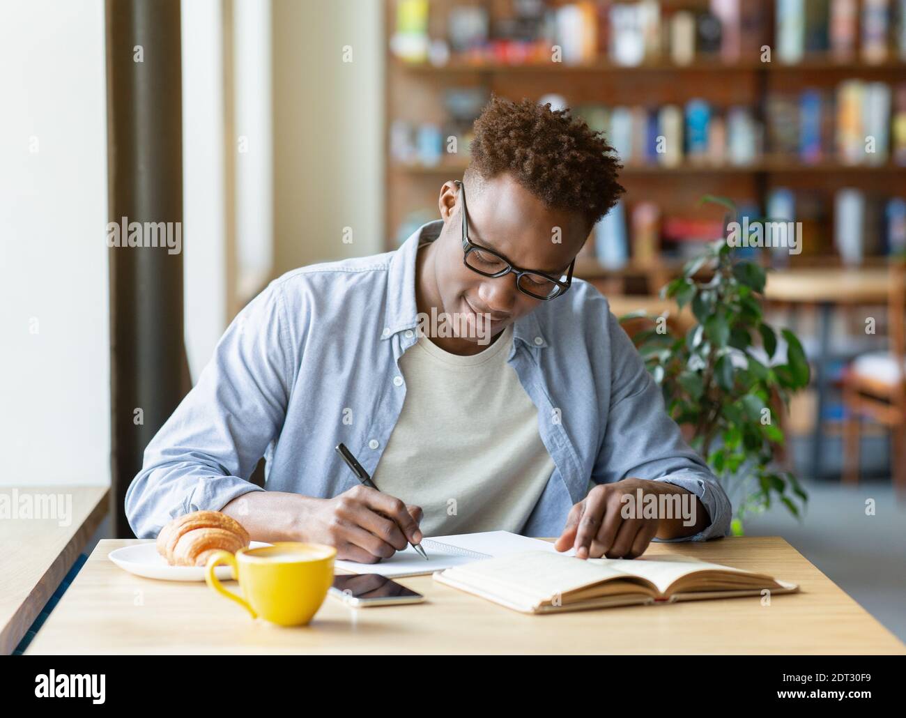 Hardworking black man writing down info from textbook, getting ready ...
